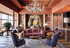 Um quarto espaçoso com um grande candelabro, um sofá vermelho e uma estante cheia de livros.