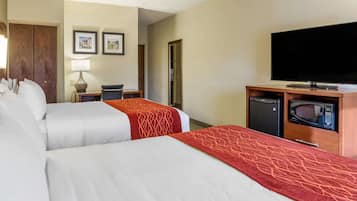Quarto de hotel com duas camas, televisão, micro-ondas e secretária com candeeiro.