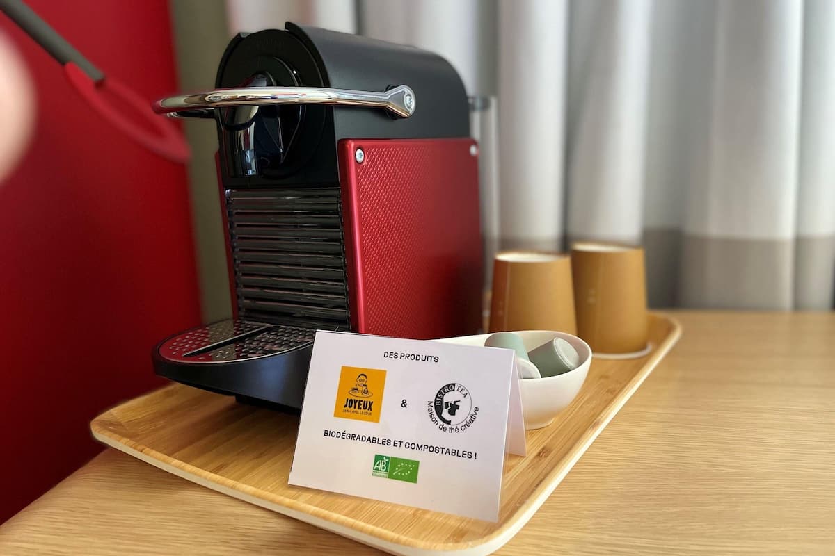 Máquina de café sobre um tabuleiro com aviso indicando produtos biodegradáveis e compostáveis.