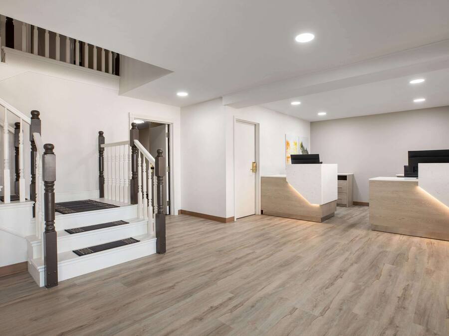 Um amplo espaço de recepção com escada de madeira, balcão de atendimento e design de interiores moderno.