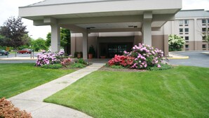 Um edifício com entrada coberta, gramado bem cuidado e plantas floridas.