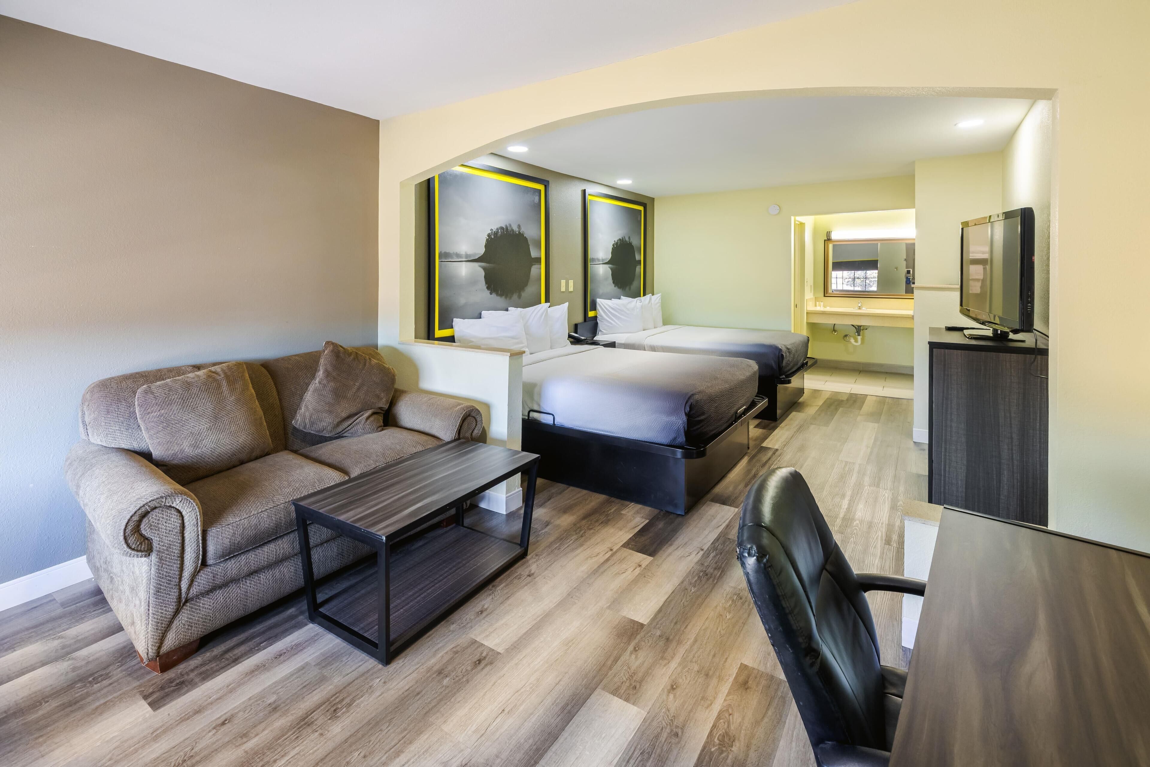Quarto de hotel moderno com sofá, cama, escrivaninha e televisão.