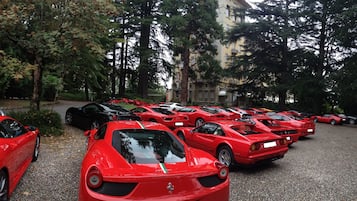 Um estacionamento cheio de carros esportivos vermelhos, rodeado por árvores e um edifício ao fundo.