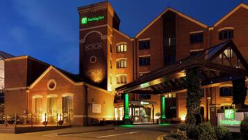 Um hotel Holiday Inn com fachada de tijolos, várias janelas e uma entrada destacada com cobertura.