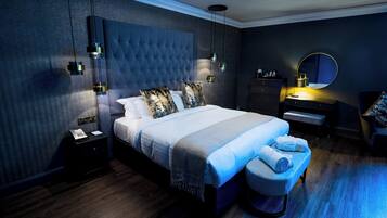 Quarto de hotel moderno com uma cama grande, mesas de cabeceira, um banco, um espelho e um guarda-roupa.