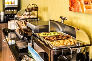 Buffet com diversos pratos, incluindo carnes, batatas e legumes.