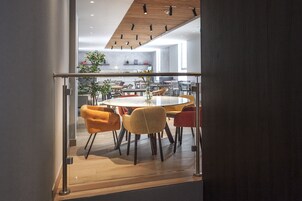 Uma área de refeições moderna com uma mesa redonda e cadeiras, uma divisória de vidro e teto de madeira.