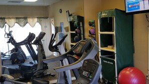 Academia com esteiras, elípticos, bicicleta ergométrica e diversos equipamentos de exercício.