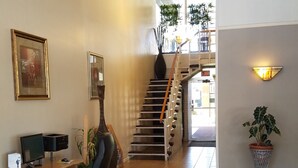 Um espaço de escritório moderno com uma mesa, computador e cadeira de escritório. Há uma escada que leva a um andar superior com plantas e um corrimão.