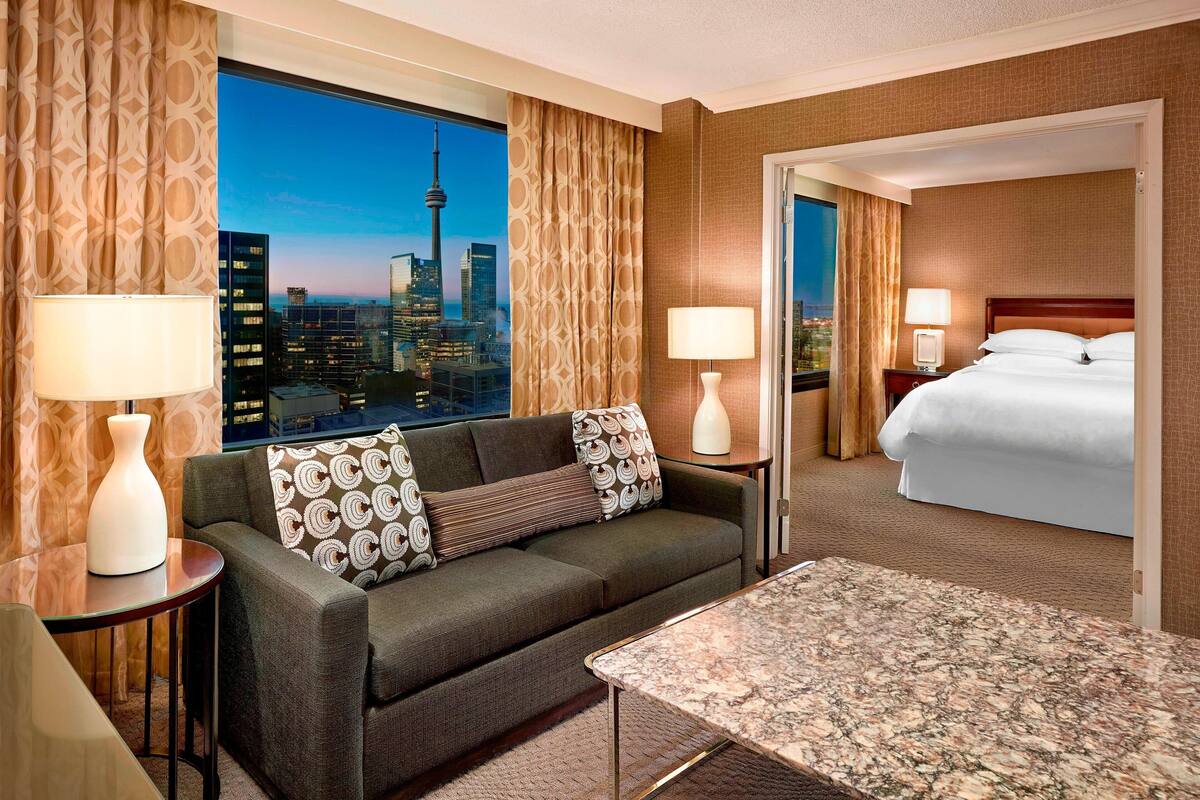 Quarto de hotel com vista para a cidade, um sofá, uma cama e uma mesa.