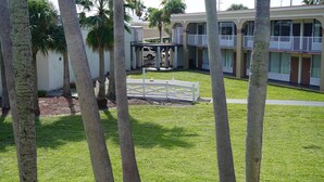 Um hotel com área de piscina, palmeiras e um edifício com varandas.