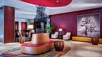 Um lobby moderno com área de estar curvada, uma grande escultura abstrata e uma grande moldura com uma imagem de uma árvore.