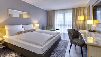 Quarto de hotel com uma cama grande, uma escrivaninha, uma cadeira e um espelho.