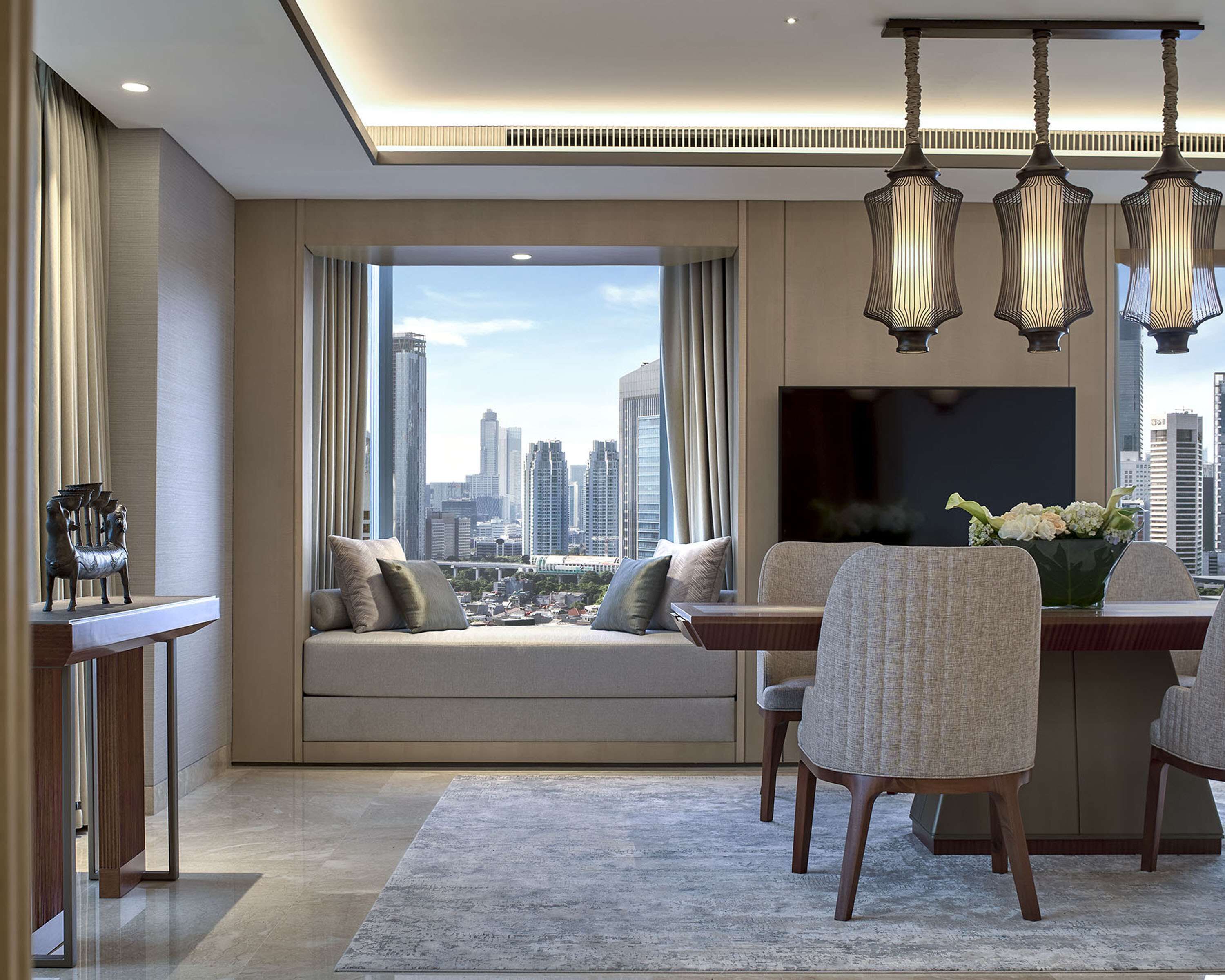 Uma sala de estar moderna com vista para a cidade, um sofá, uma mesa de jantar e luminárias pendentes.