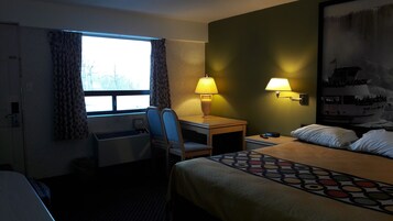 Quarto de hotel com cama, escrivaninha, cadeira, janela com cortinas, duas luminárias de parede e um quadro na parede.