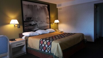 Quarto de hotel com uma cama, duas luminárias de cabeceira, um telefone, uma cadeira e um mural grande na parede retratando uma cascata.