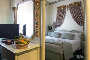 Quarto de hotel com uma cama, uma escrivaninha com computador, uma cesta de frutas e cortinas.