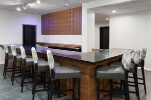 Uma sala de conferências com uma mesa comprida, seis cadeiras e uma parede de destaque em madeira.