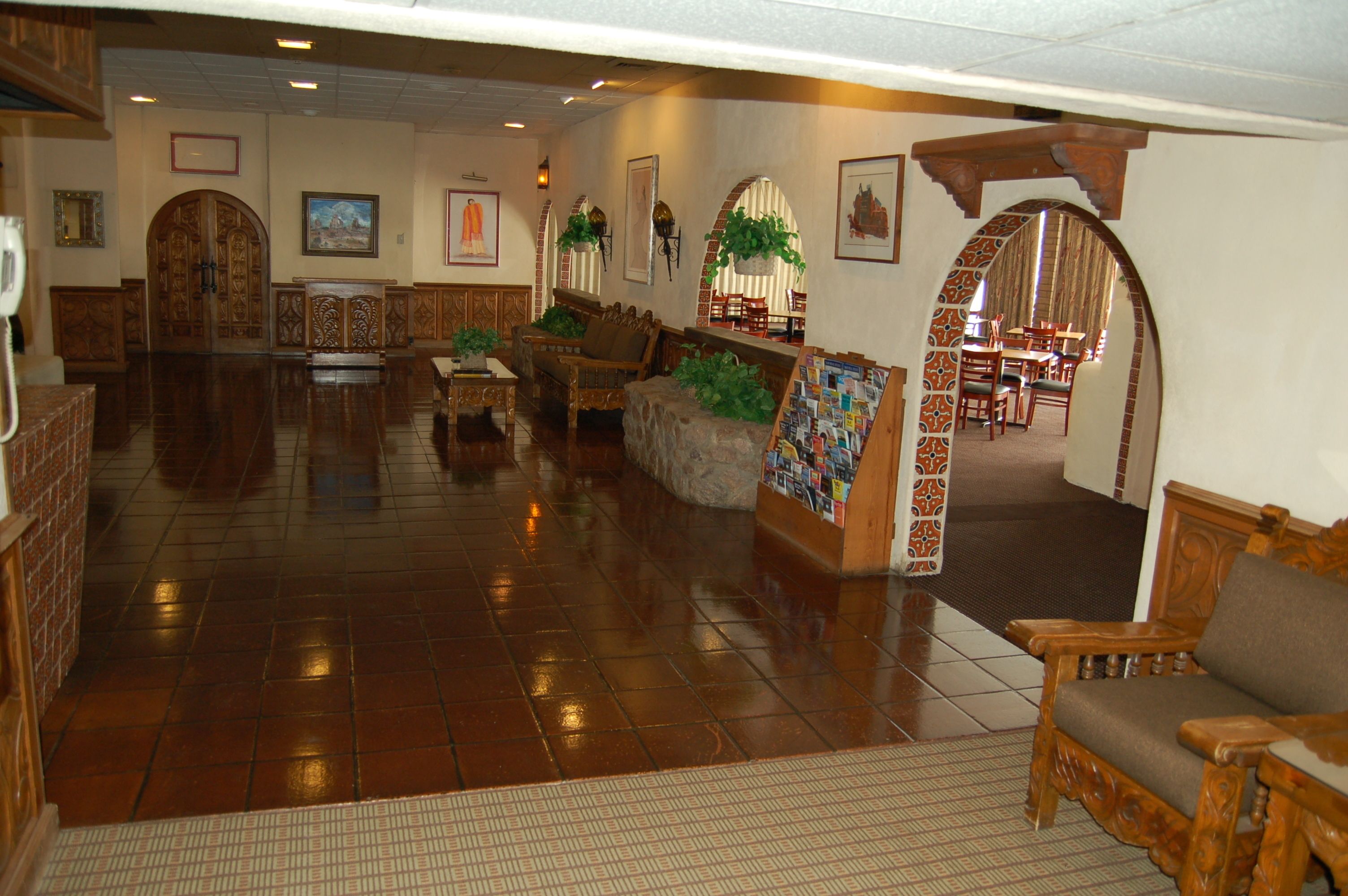 Um hall amplo com piso de madeira lustrosa, um balcão de recepção e uma área de estar com mobiliário de madeira.
