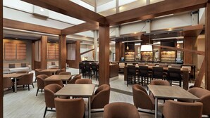 Um restaurante moderno com pé-direito alto, vigas aparentes e um espaço de bar.