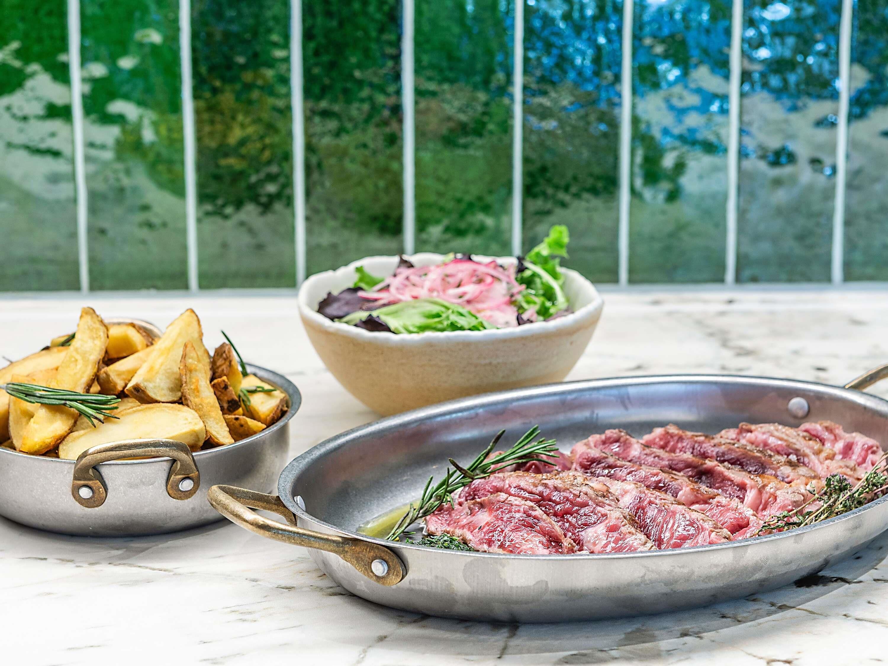 Uma refeição com carne assada, batatas e salada sobre a mesa.