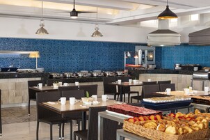 Um restaurante espaçoso com tetos altos, paredes de mosaico azul e mobiliário moderno.
