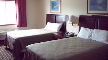 Quarto de hotel com duas camas, mesa de cabeceira com abajur, telefone e janela com cortinas.