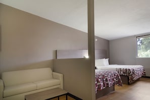 Quarto com sofá, duas camas com colchas xadrez, janela e luminária fixada na parede.
