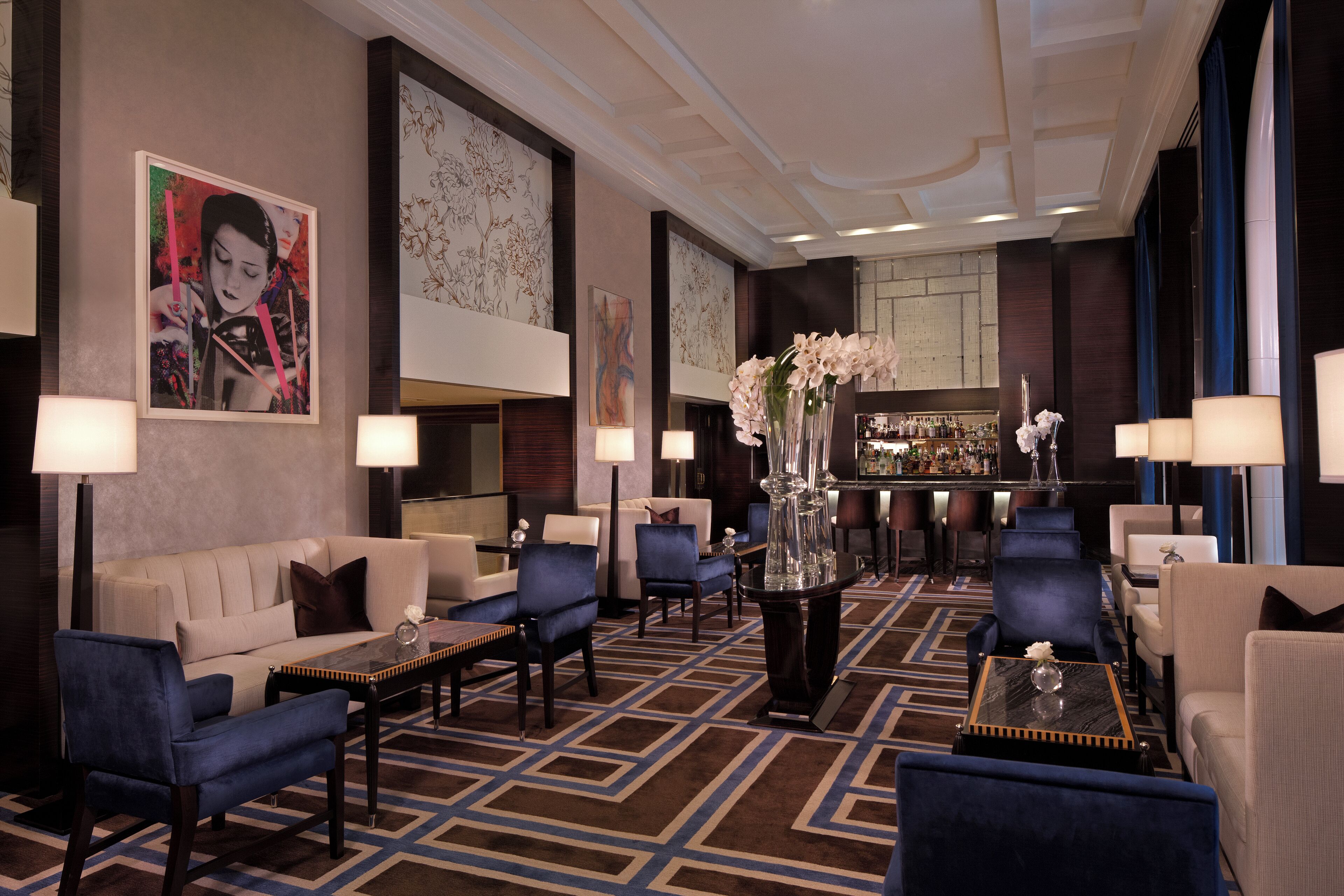 Um saguão de hotel com área de bar, assentos e elementos decorativos.