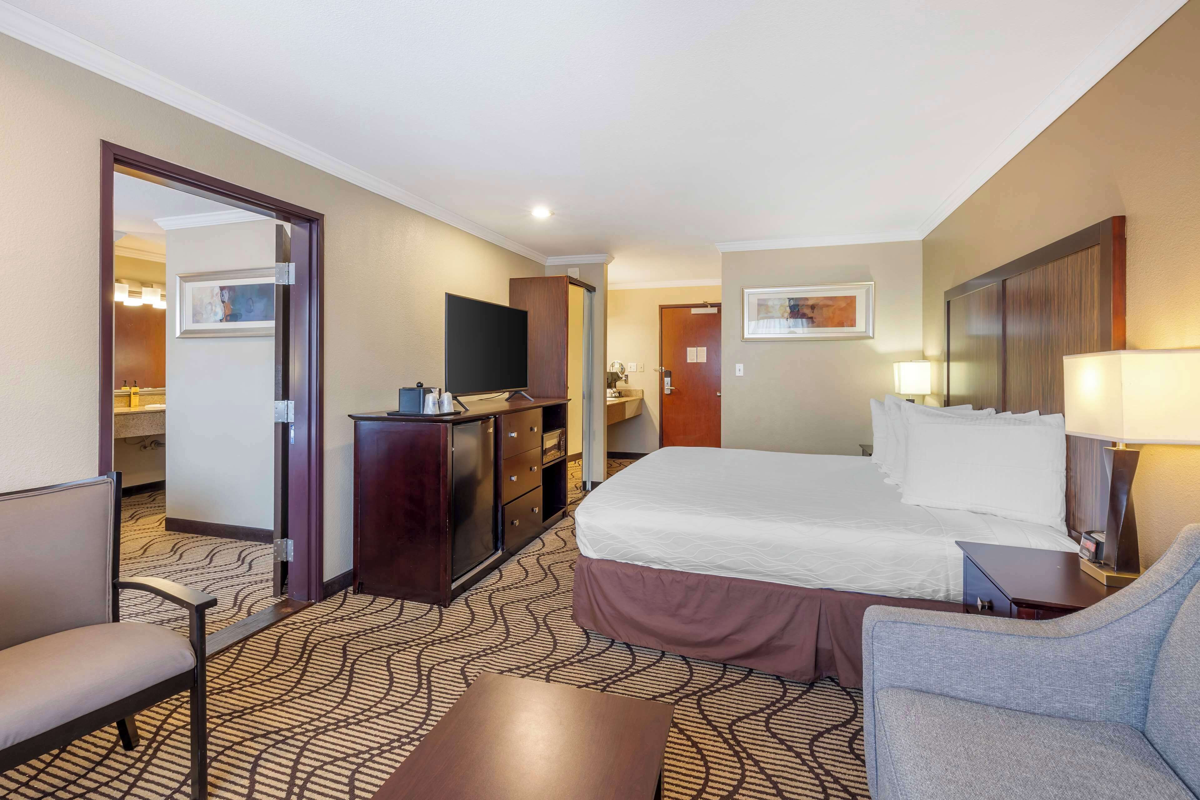 Quarto de hotel com uma cama grande, uma escrivaninha, uma cadeira, uma televisão e um guarda-roupa.