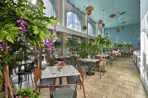 Um restaurante interno com mesas, cadeiras e cestos suspensos com flores.