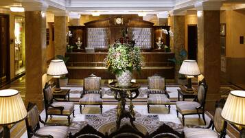 Um lobby com arranjo floral central, área de estar e um relógio na parede.