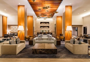 Um hall espaçoso com área de estar central, tetos altos e um lustre moderno.