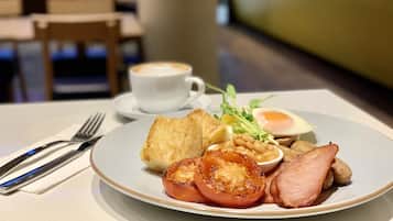 Prato de café da manhã com torradas, ovos, tomates, feijão e presunto.