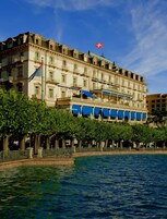 Um hotel histórico com estilo arquitetônico europeu clássico, com várias varandas e uma bandeira.