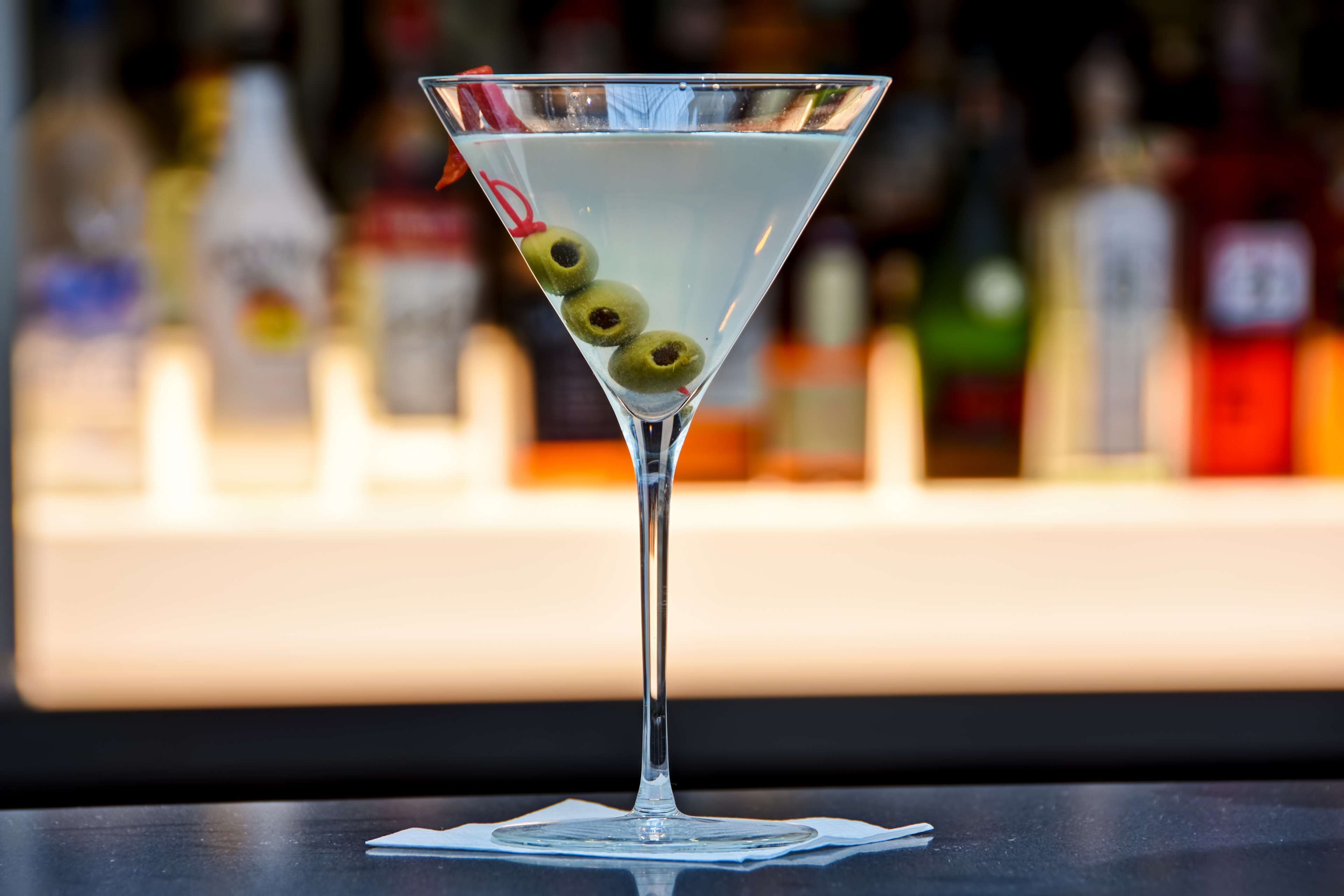 Um copo de martini com azeitonas em um balcão de bar.