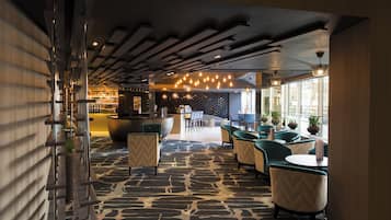 Uma área de bar moderna, com piso de padrão em pedra, assentos e balcão.