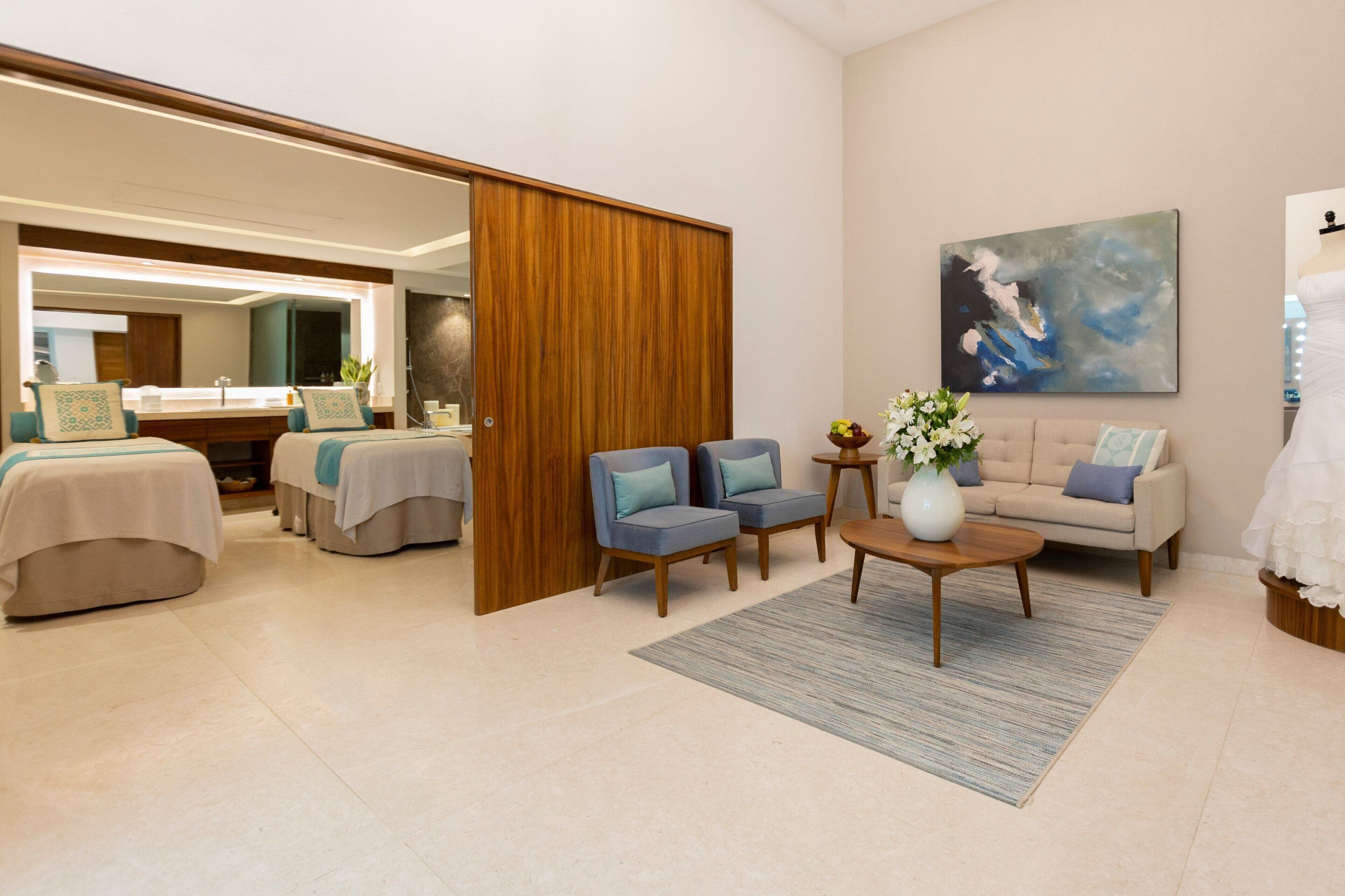 Um lobby moderno de hotel com balcão de recepção, área de estar e uma pintura grande na parede.