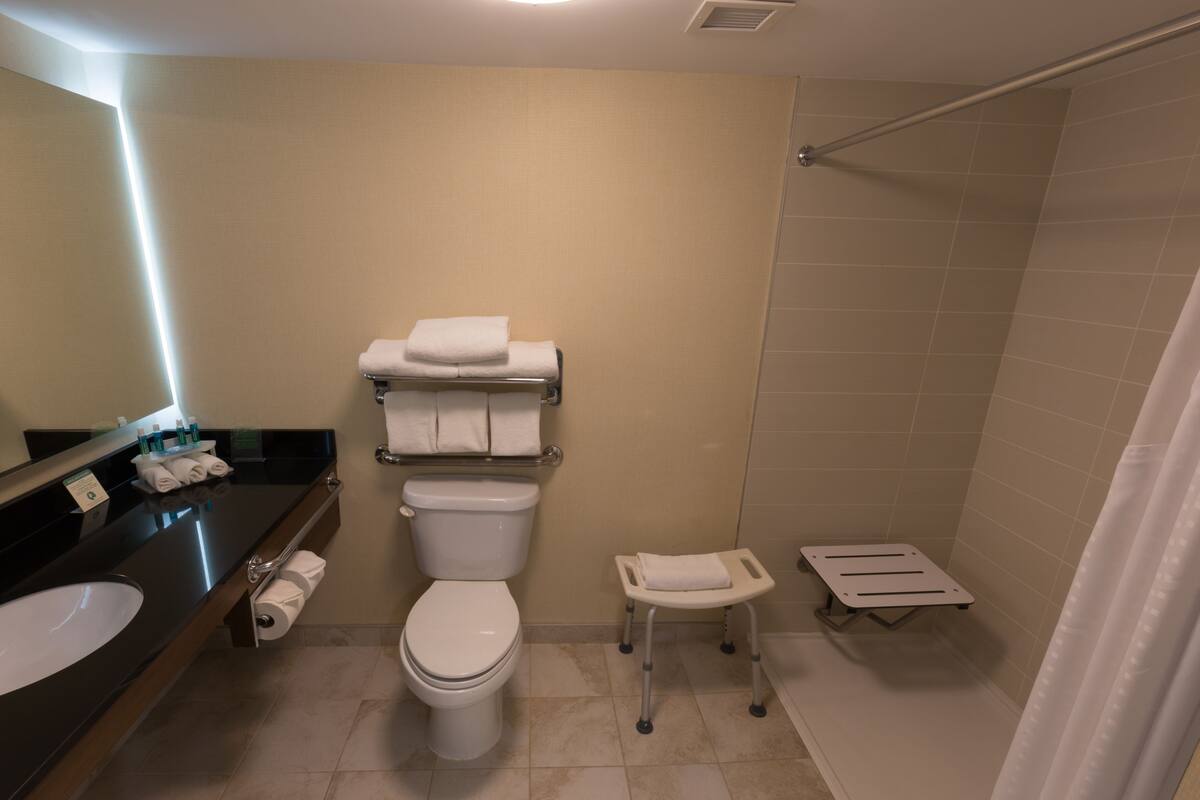Uma casa de banho moderna com sanita, lavatório e chuveiro.