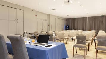 Sala de conferências com uma mesa azul, laptops e cadeiras.