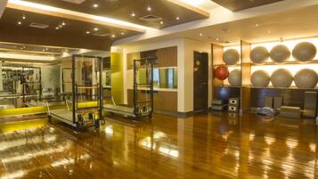 Academia com equipamentos de ginástica, espelho e uma parede de bolas de exercício.