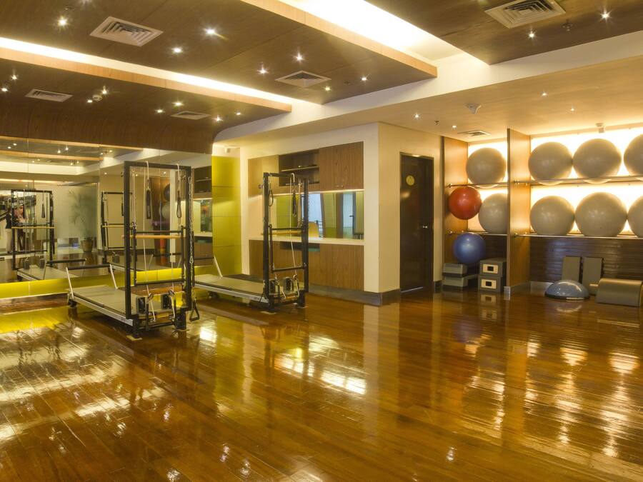 Academia com equipamentos de ginástica, espelho e uma parede de bolas de exercício.