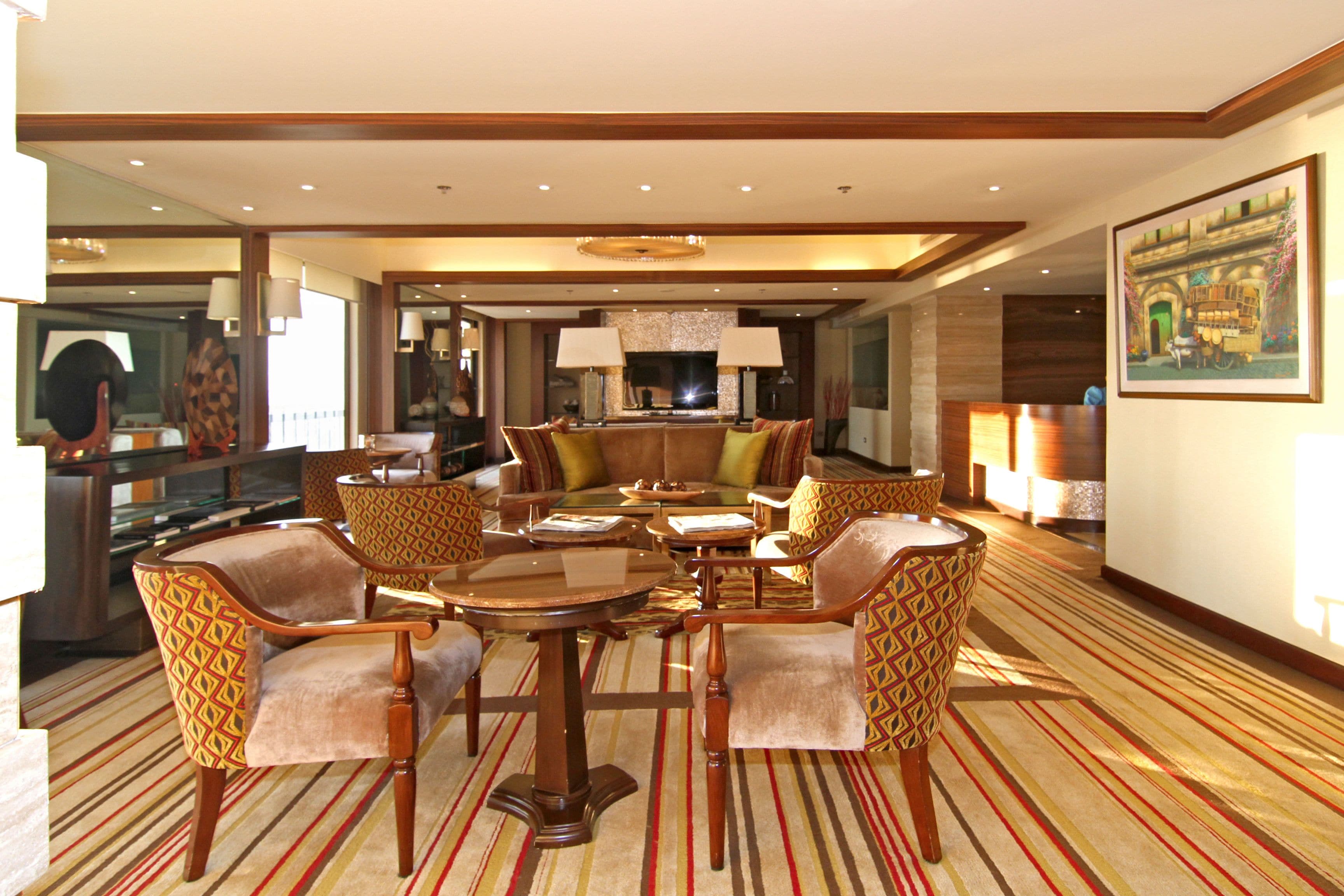 Um hall de hotel com área de estar central, uma televisão e um balcão de recepção.