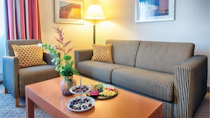 Uma sala de estar moderna com sofás listrados, uma mesa de centro com lanches e uma luminária.
