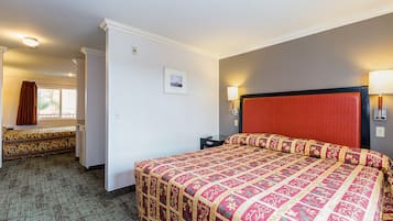 Quarto de hotel com uma cama grande, mesa de cabeceira, cortinas e um quadro na parede.