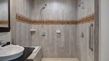 Casa de banho com lavatório, espelho, chuveiro e chão em azulejos.
