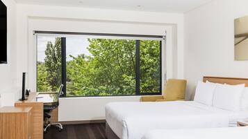Quarto de hotel com uma janela grande, uma mesa, uma cama e uma cadeira.