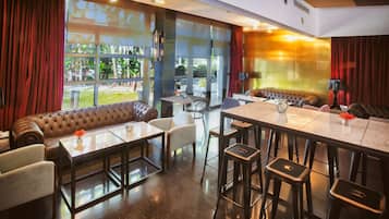 Uma área de bar moderna com disposição de banquetas, um banco acolchoado e uma mesa de vidro.