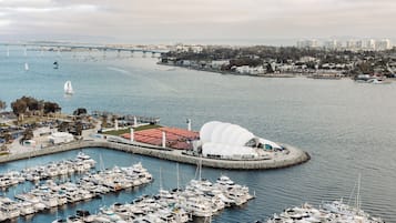 Uma marina com vários barcos atracados, um edifício branco com um telhado curvo e uma ponte ao fundo.