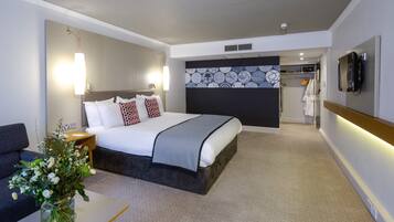 Quarto de hotel moderno com uma cama grande, mesa de cabeceira e um vaso de flores.